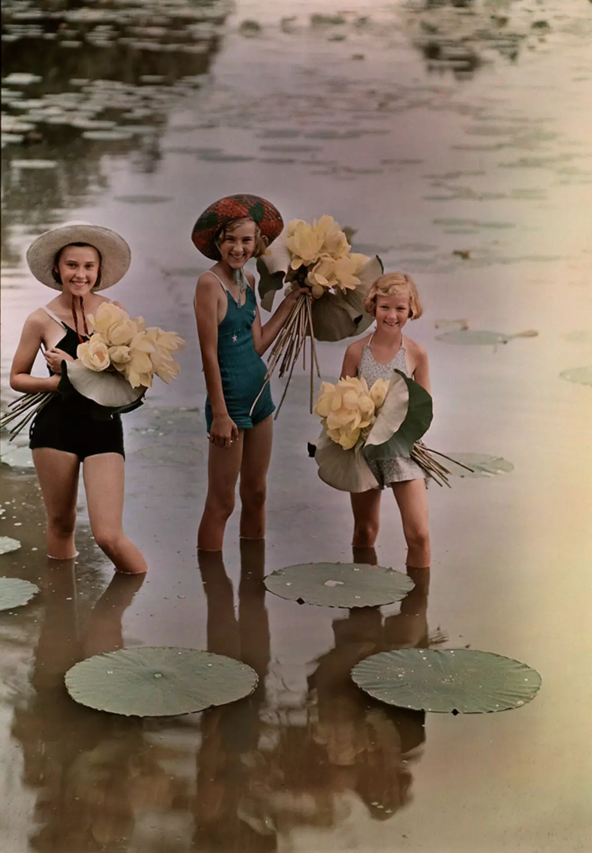 28. Ang mga batang babaye nagbarug sa tubig, nga naggunit mga bouquets gikan sa yellow lotus sa mga kamot. Aman, Iowa, Nobyembre 1938 National Geographic, Kasaysayan, Kinaiyahan, Potograpiya