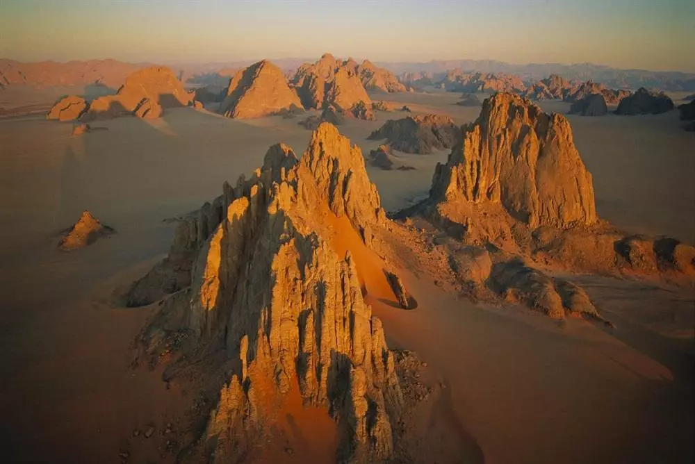 1. Kamasai Valley in Tsjad. Sandstone heuwels maak hul pad deur oranje duine in die Tibesta-streek